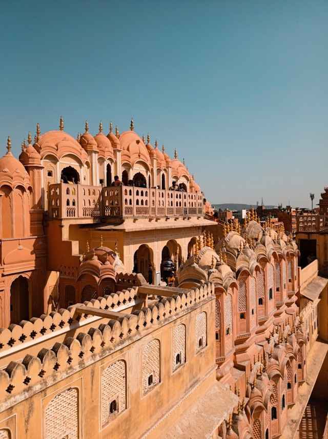 Terracotta-colored palace with intricate architecture under blue sky.